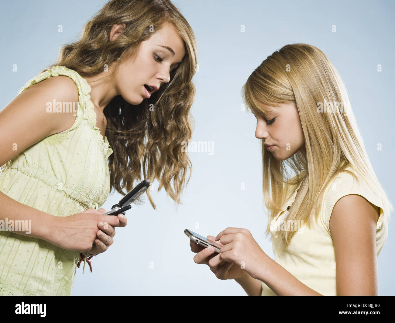 Two girls with cell phones smiling Stock Photo - Alamy