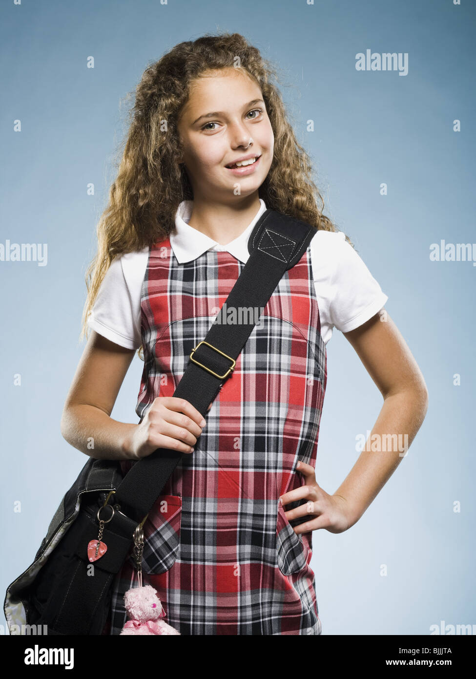 Schoolgirl standing with school bag smiling Stock Photo - Alamy