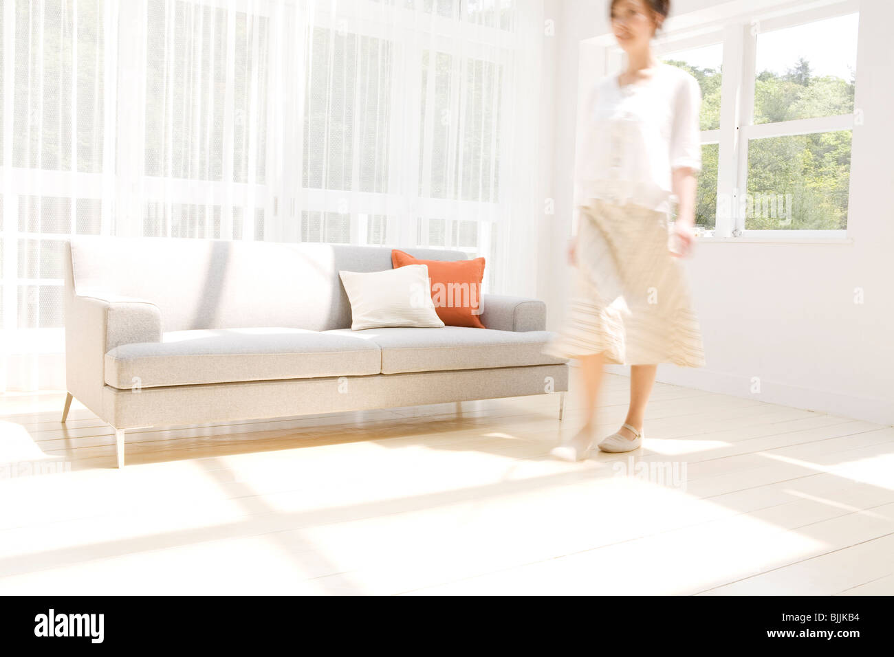 Woman walking in living room Stock Photo - Alamy