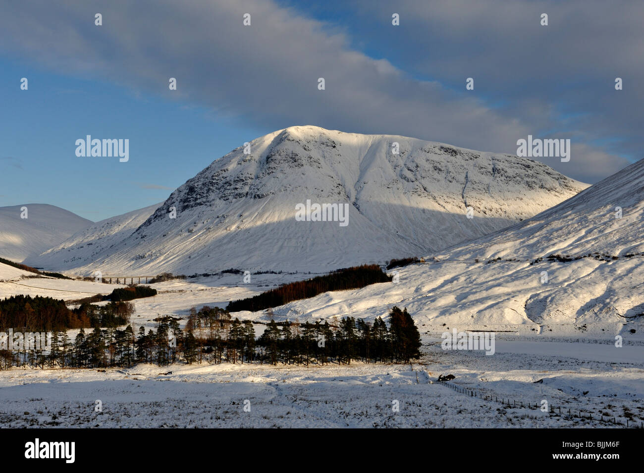 Vista of snowy mountains and blue sky seen across a wide snow-filled ...