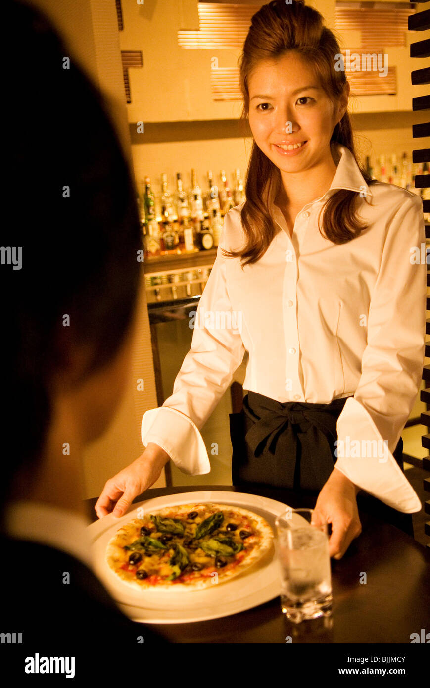 Waitress bringing a pizza to a table Stock Photo - Alamy