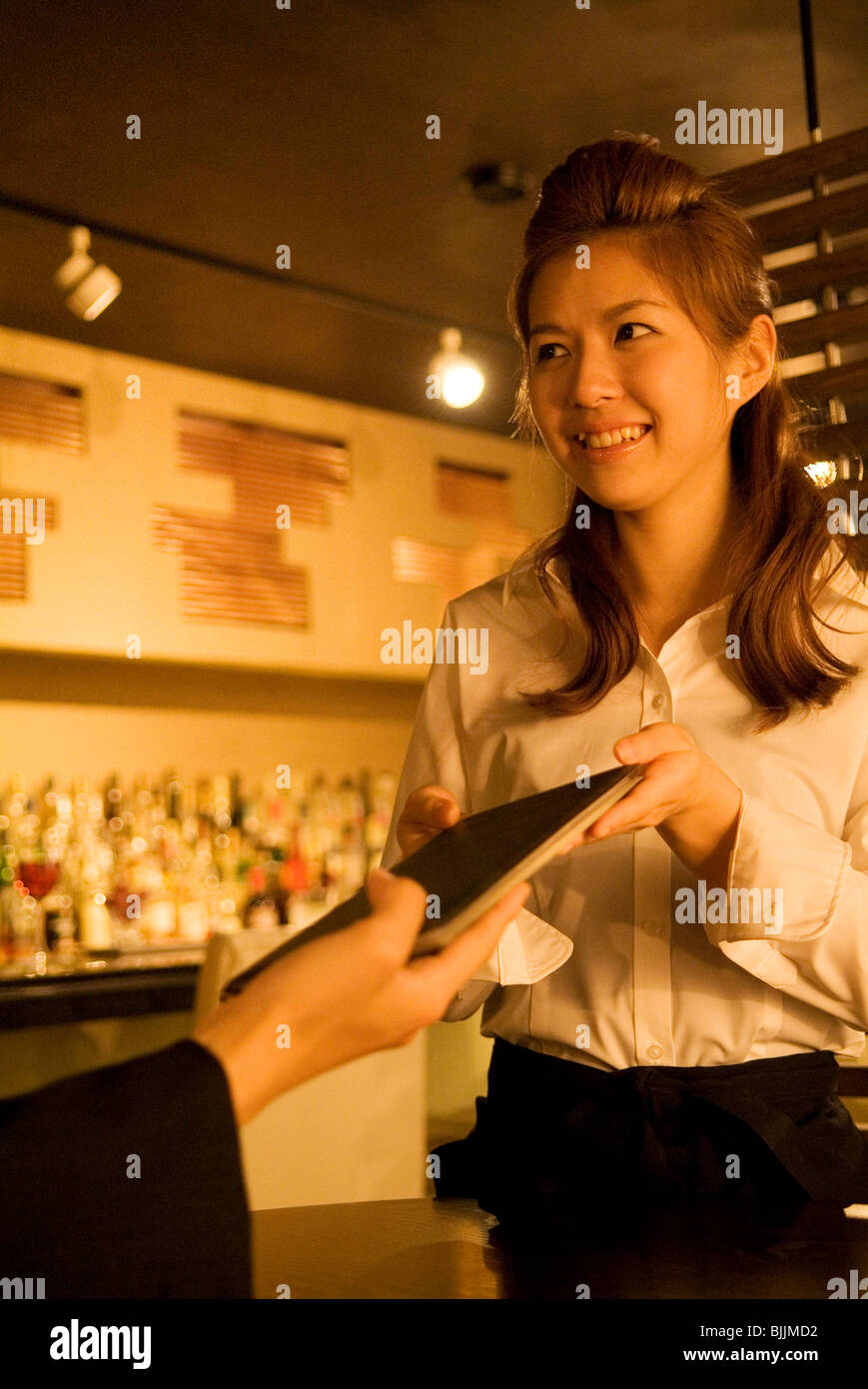 Waitress handing a menu to a customer Stock Photo - Alamy