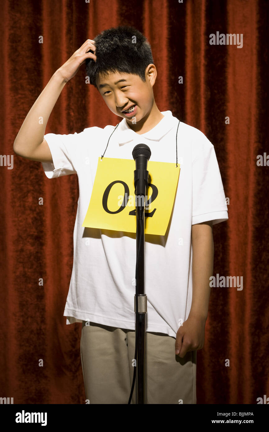 Boy at microphone with number around neck scratching head Stock Photo ...