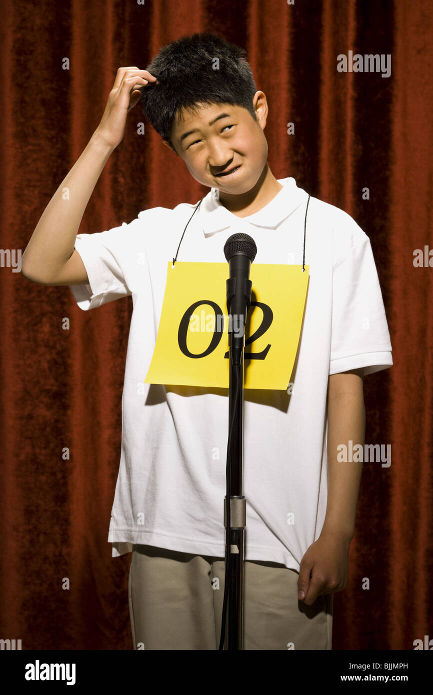 Boy at microphone with number around neck scratching head Stock Photo ...