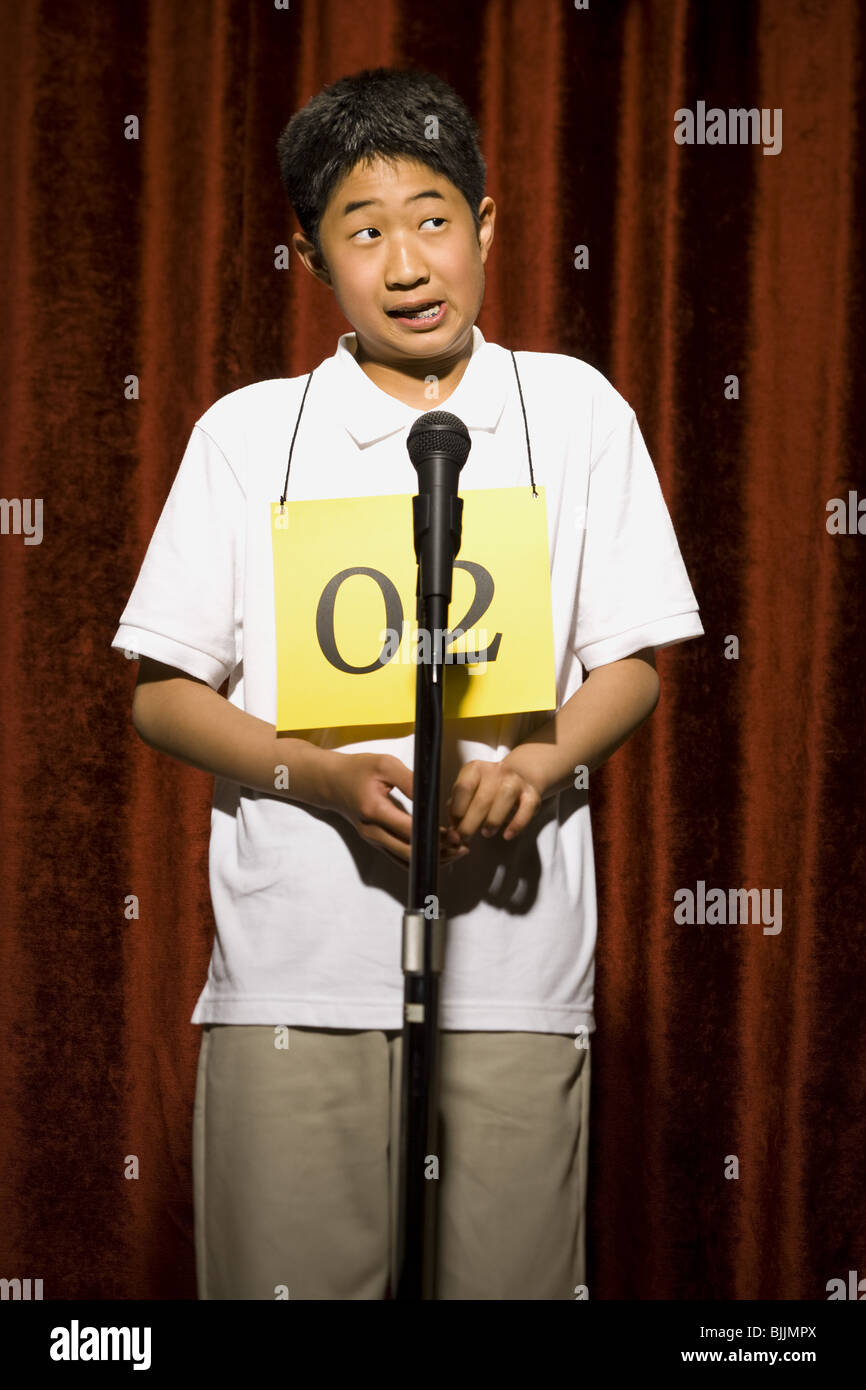 Boy at microphone with number around neck scratching head Stock Photo ...