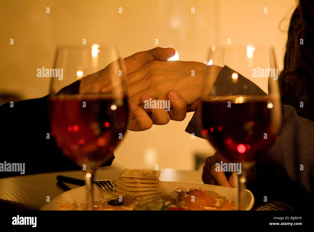 Couple holding hands over a table Stock Photo - Alamy