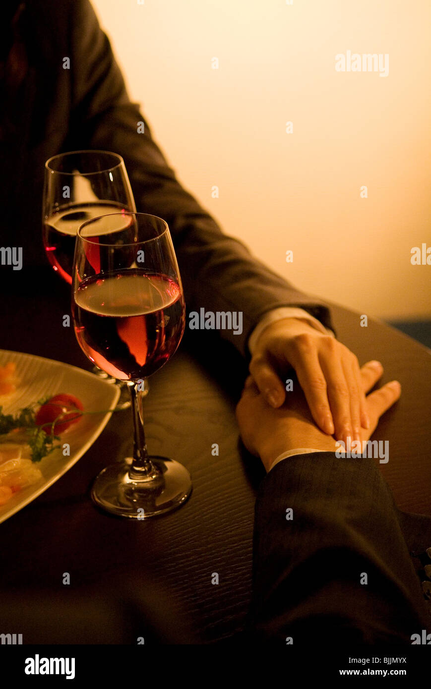 Couple holding hands over a table Stock Photo - Alamy