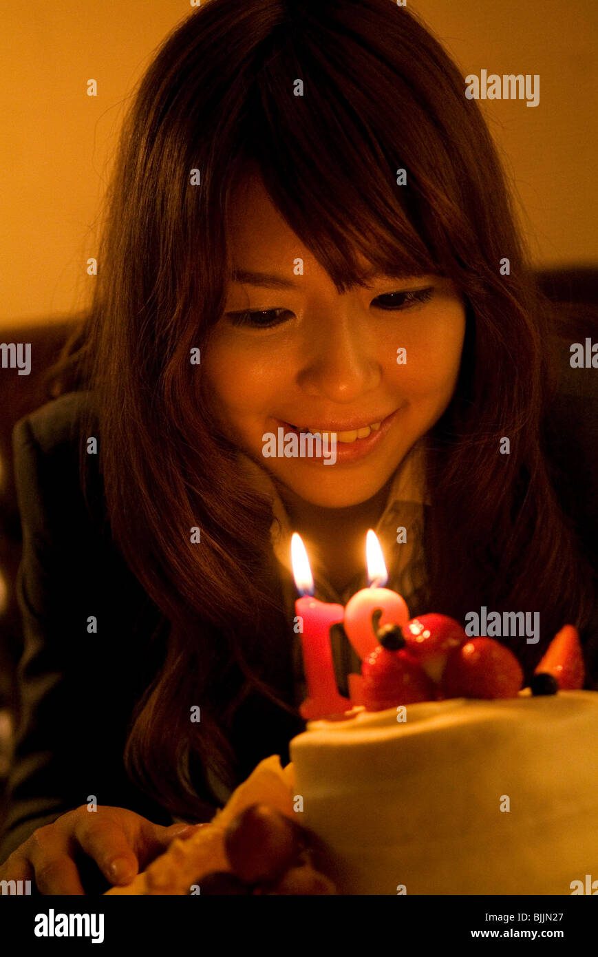 Woman Leaning Over To Blow Out The Candles On Her Birthday Cake Stock