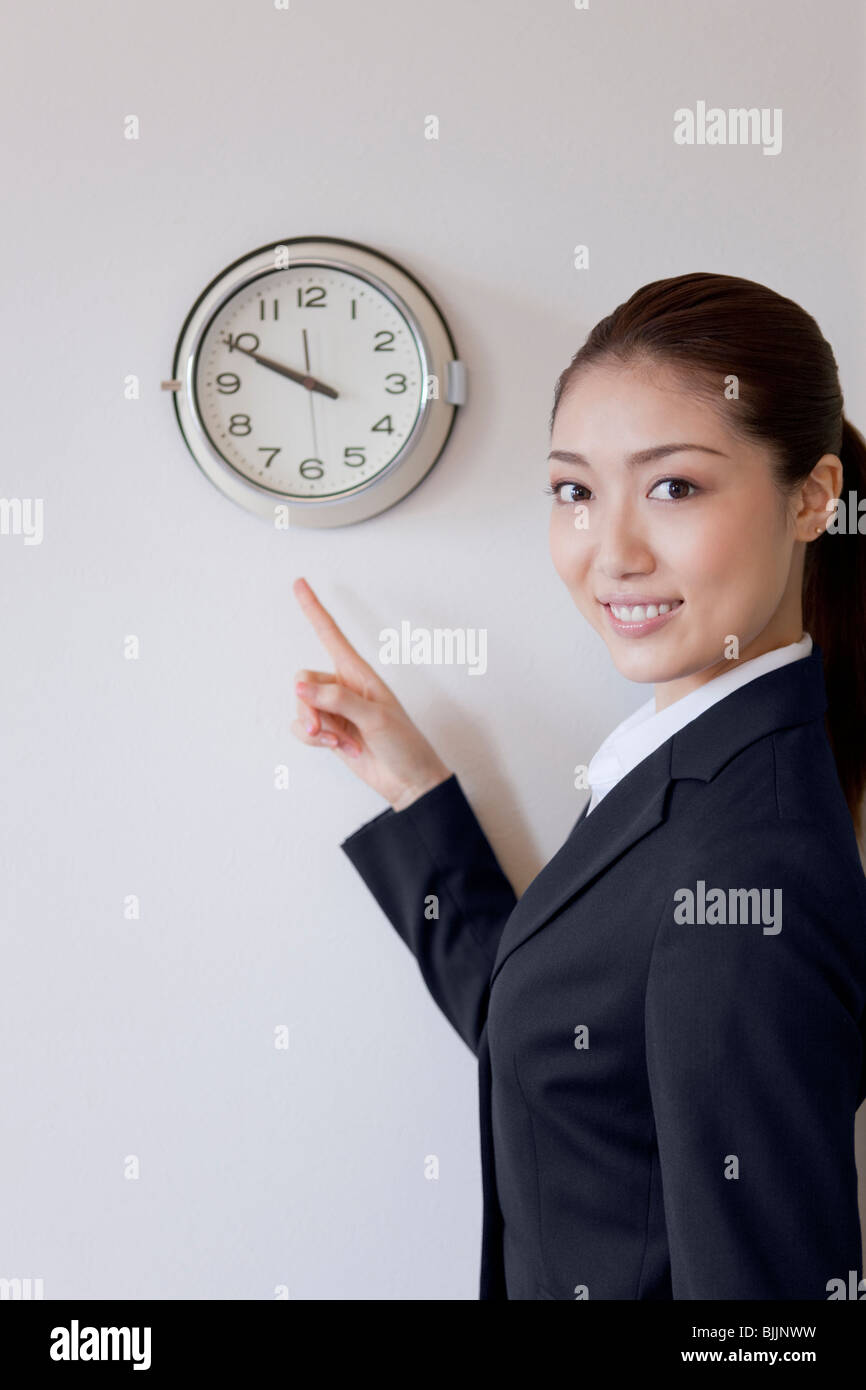 Young businesswoman pointing at clock Stock Photo - Alamy