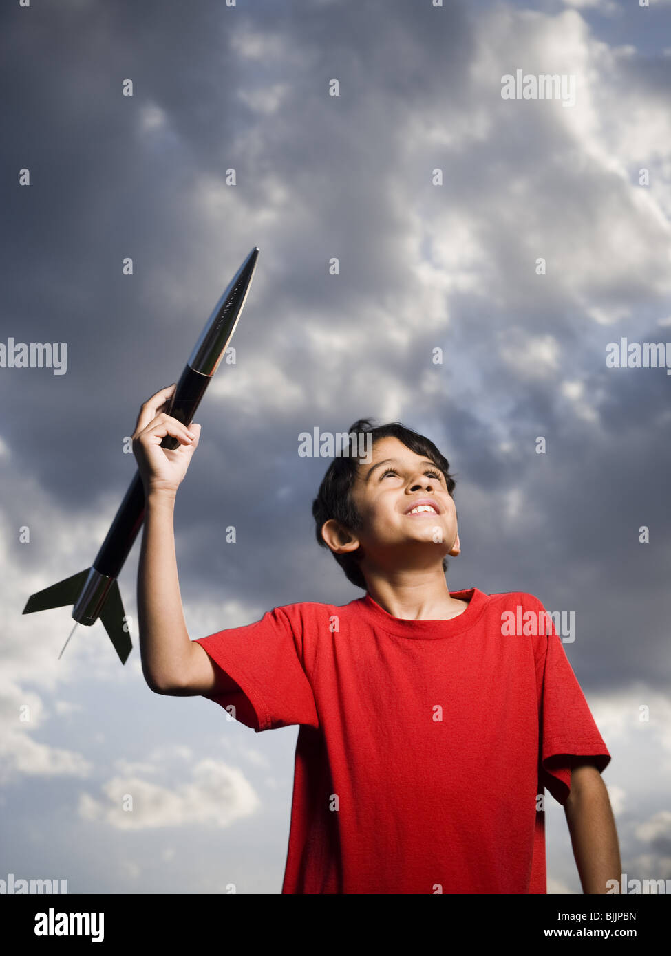 Boy playing with toy rocket outdoors on cloudy day low angle view Stock ...