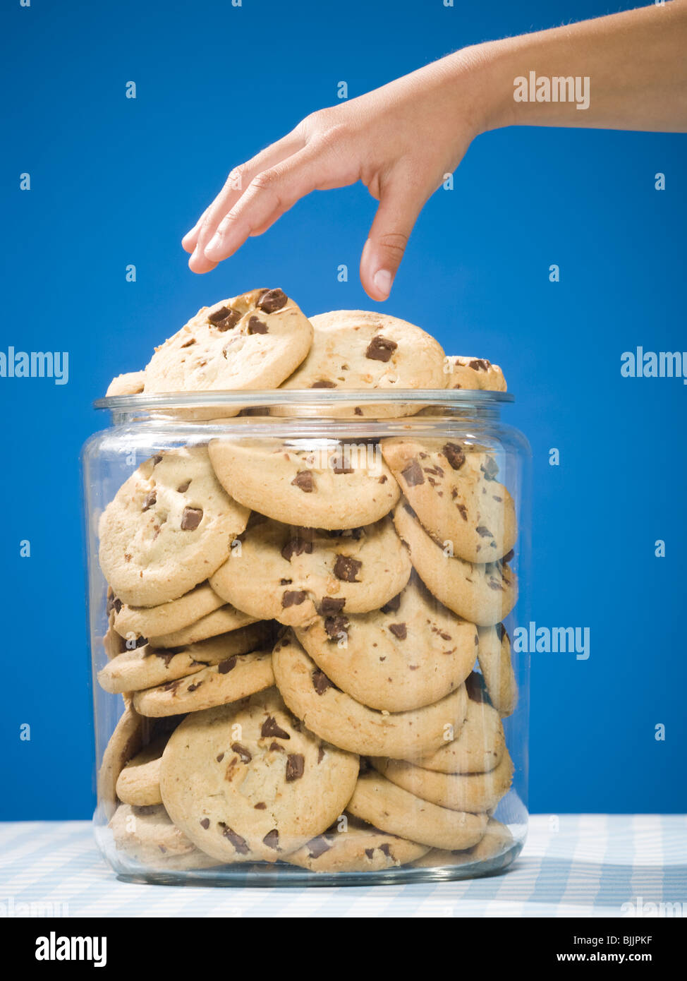 Hand grabbing chocolate chip cookie from jar Stock Photo - Alamy