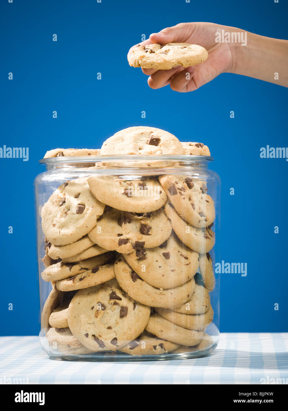 Hand grabbing chocolate chip cookie from jar Stock Photo - Alamy