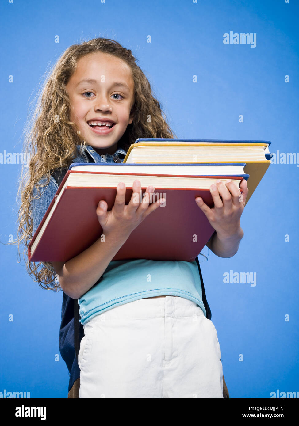 Smiling girl with backpack carrying pile of textbooks Stock Photo - Alamy