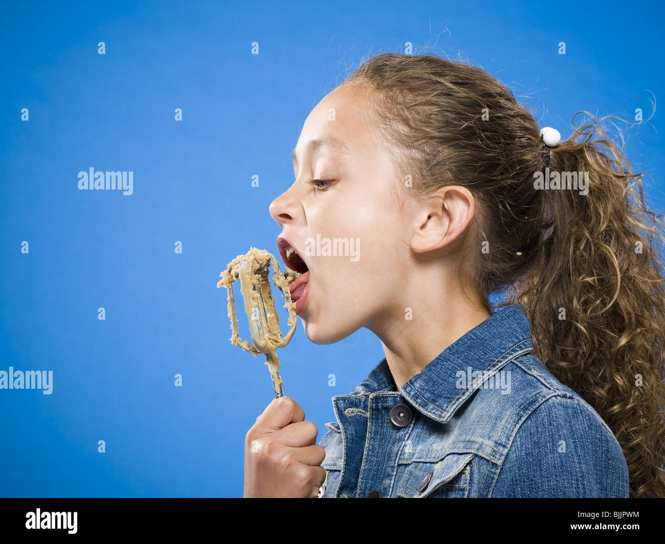 Profile of girl licking batter off beater Stock Photo - Alamy