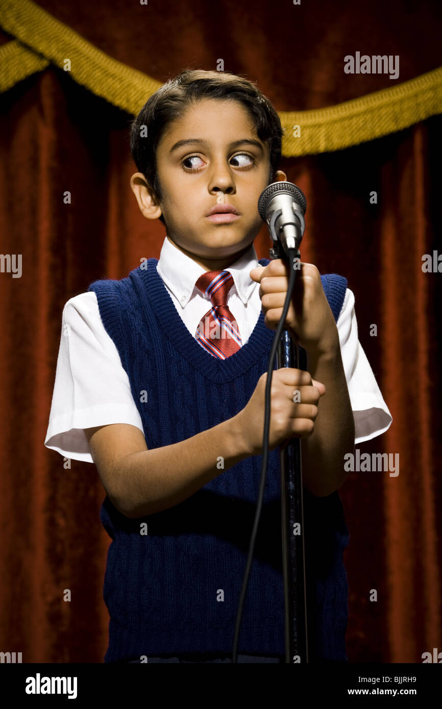 Boy standing on stage with microphone and big eyes Stock Photo - Alamy
