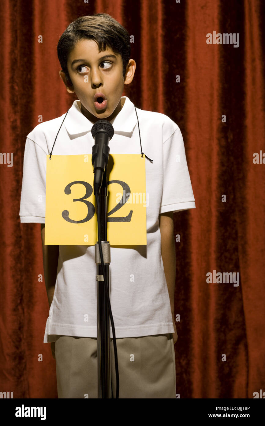 Boy standing at microphone speaking with number around neck Stock Photo ...