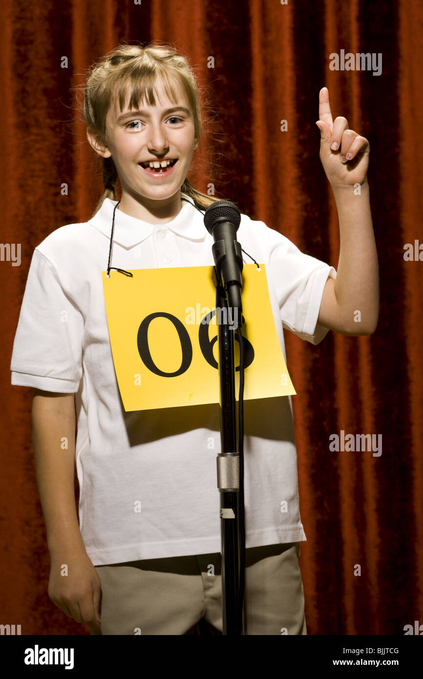 Girl contestant standing at microphone smiling and pointing up Stock ...
