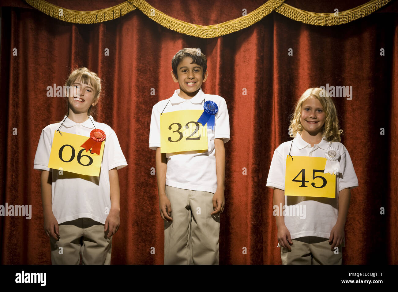Three children on stage at winner's podium with ribbons smiling Stock ...