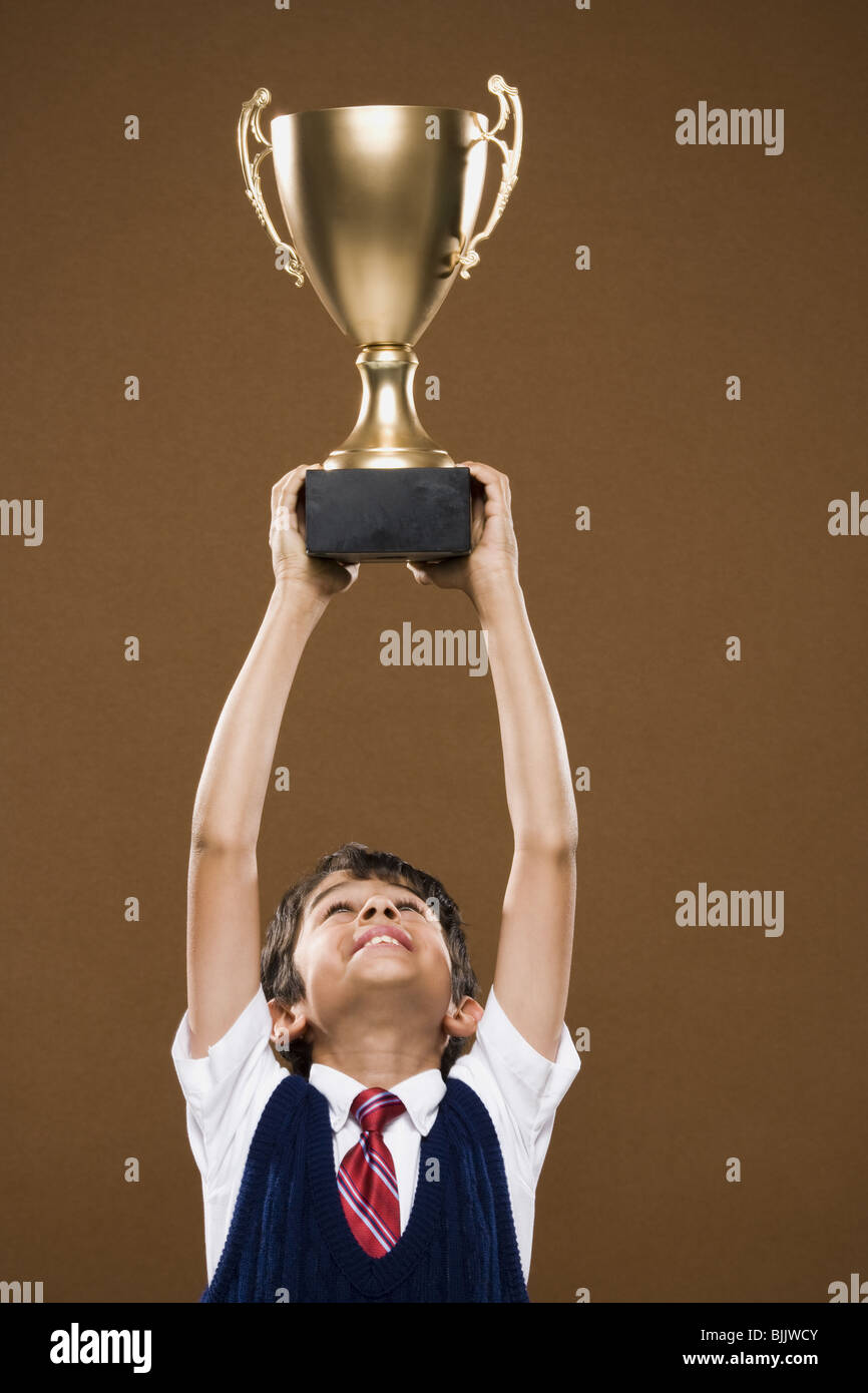 Boy holding trophy cup over head smiling Stock Photo - Alamy