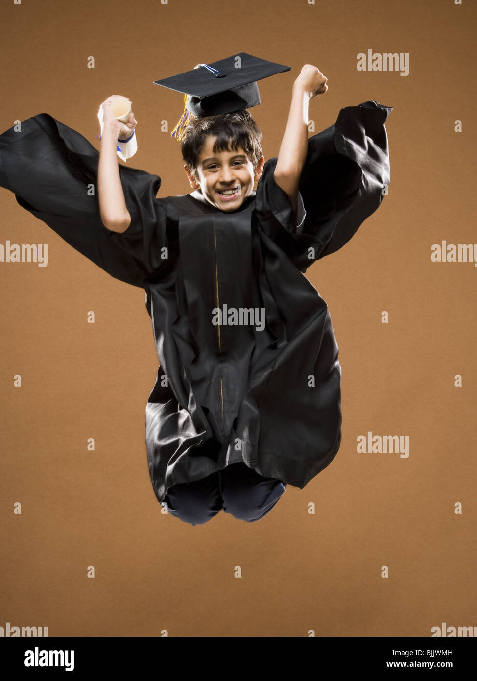 Boy graduate with mortar board and diploma leaping and smiling Stock ...