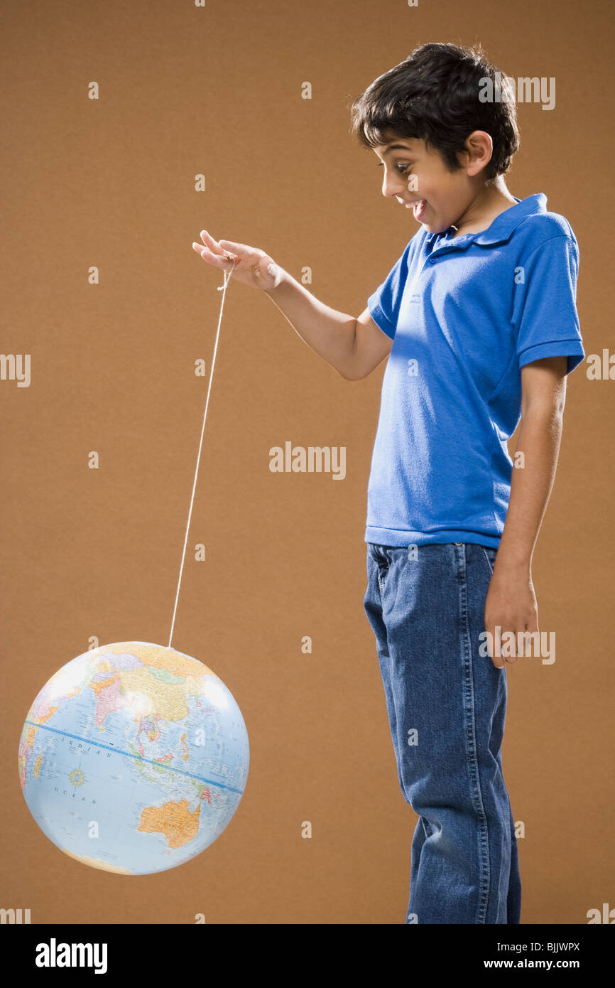 Boy holding string with globe attached smiling Stock Photo - Alamy