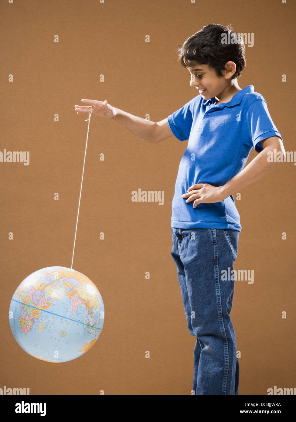 Boy holding string with globe attached smiling Stock Photo - Alamy
