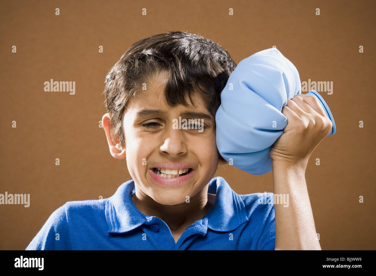 Boy holding ice pack to head Stock Photo - Alamy