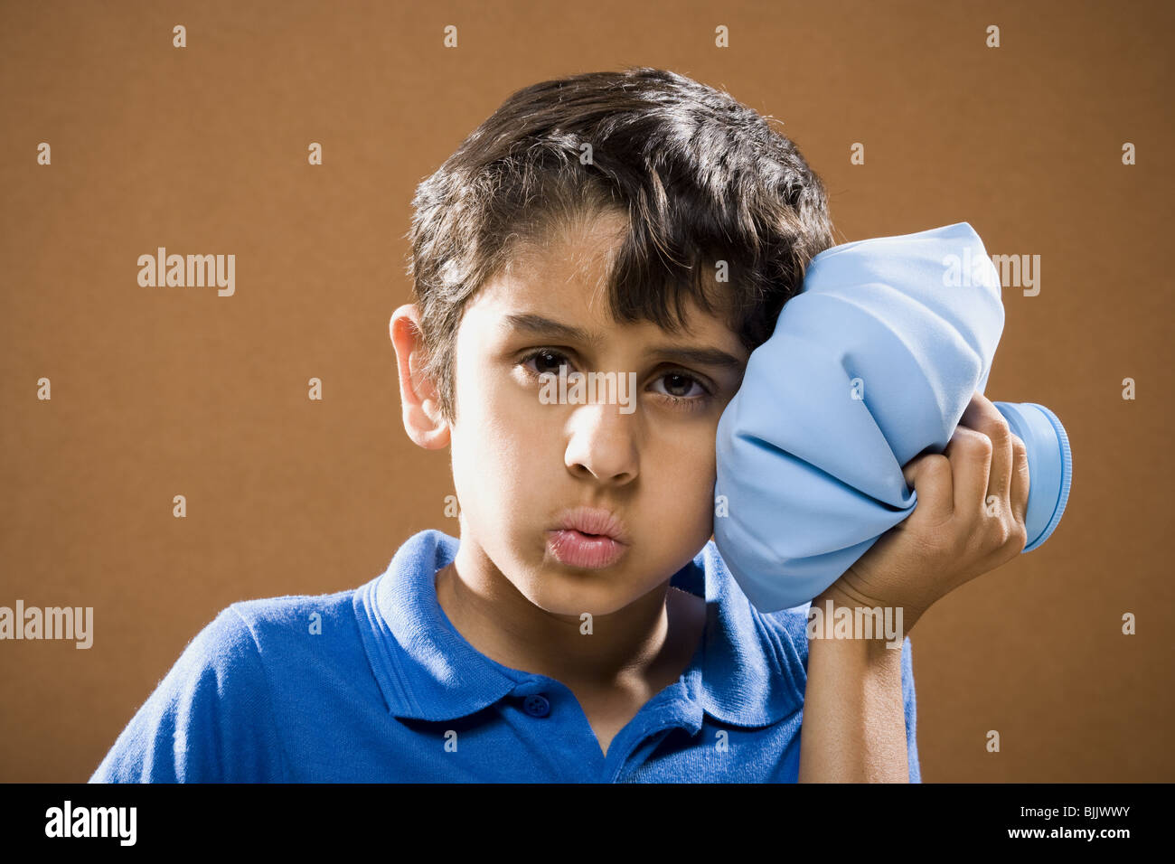 Boy holding ice pack to head Stock Photo - Alamy