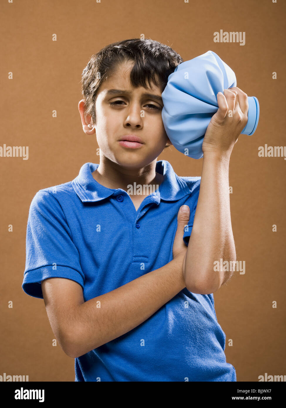 Boy holding ice pack to head Stock Photo - Alamy