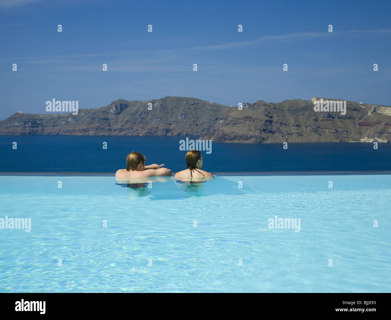 Rear view of couple in infinity pool with mountains Stock Photo - Alamy