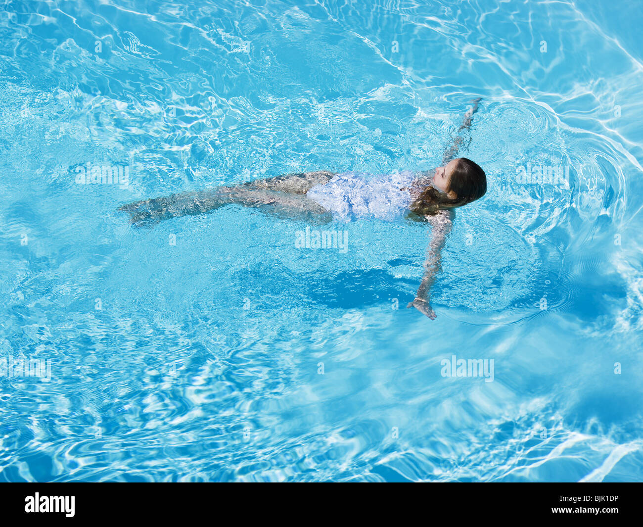 Woman floating in pool Stock Photo - Alamy