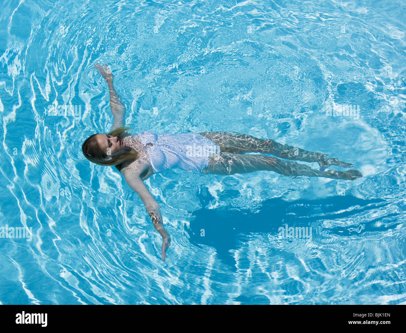 Woman floating in pool Stock Photo - Alamy