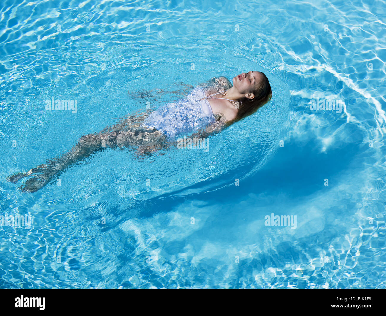 Woman floating in pool Stock Photo - Alamy
