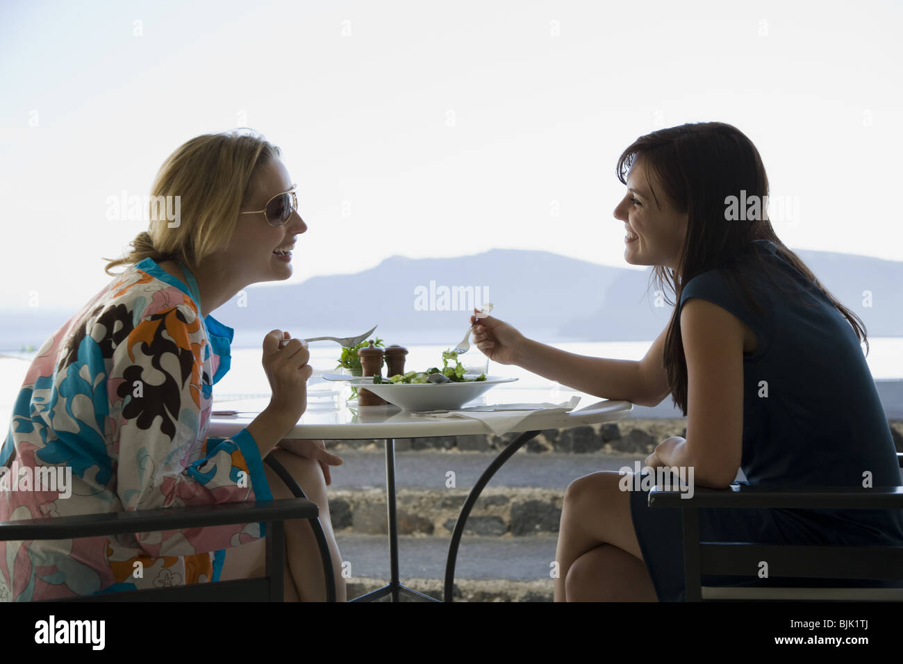 Two women eating salad outdoors and smiling with rock formation in ...