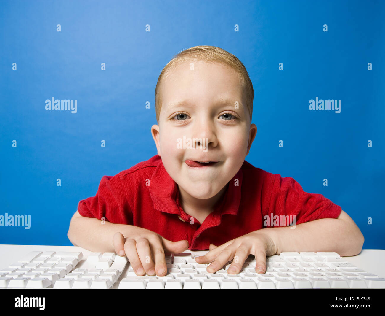 Boy sitting at keyboard smiling Stock Photo - Alamy