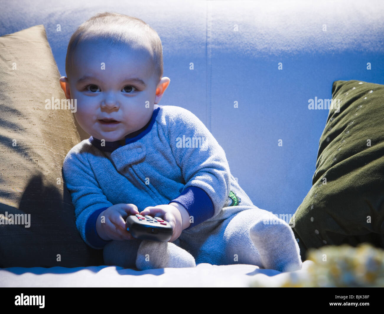 Baby on sofa with television remote Stock Photo - Alamy