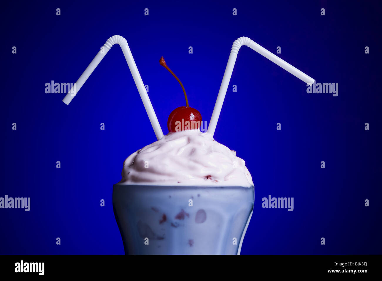 Milkshake with two straws and maraschino cherry Stock Photo - Alamy
