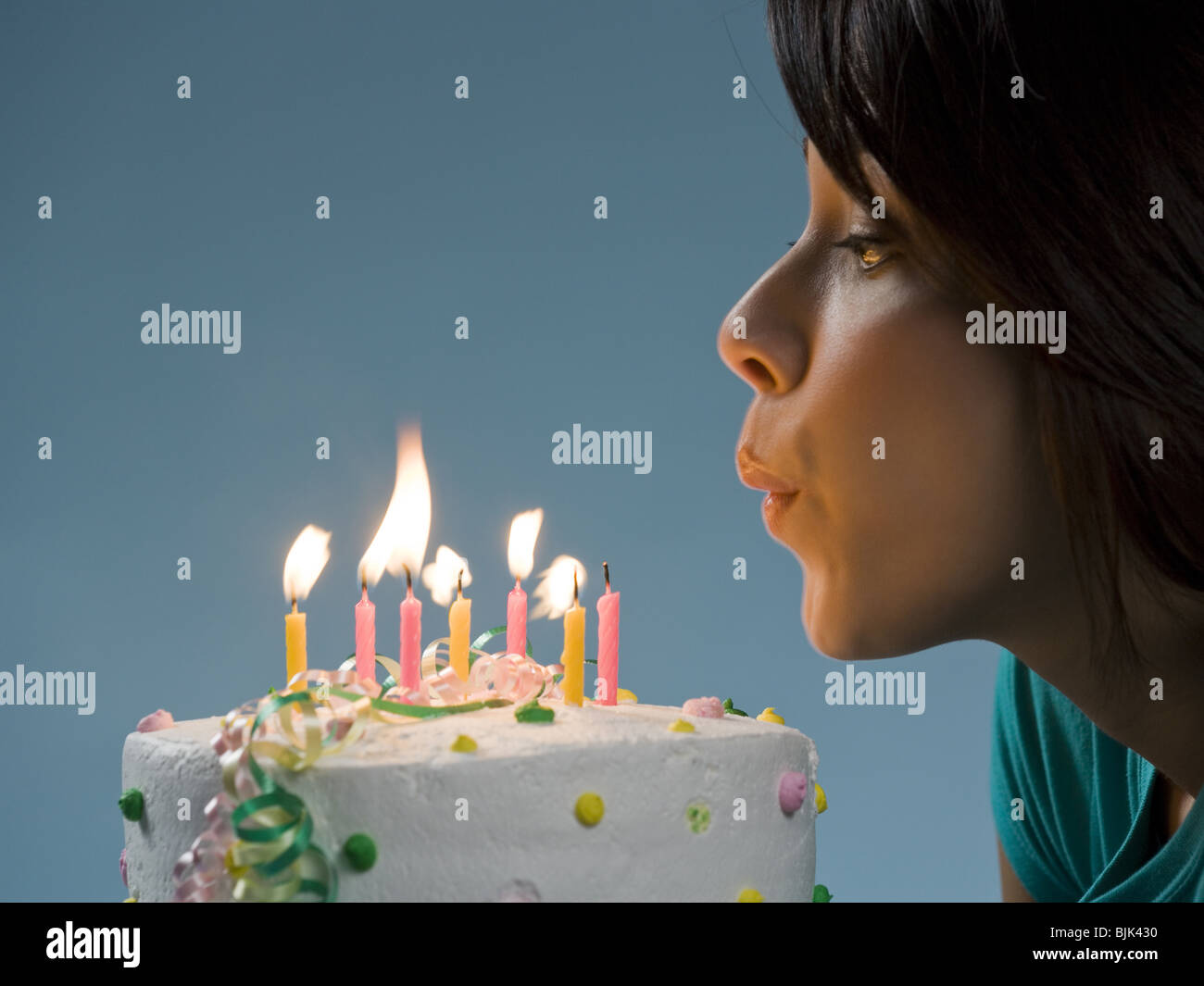 Profile of woman blowing out candles on birthday cake Stock Photo - Alamy