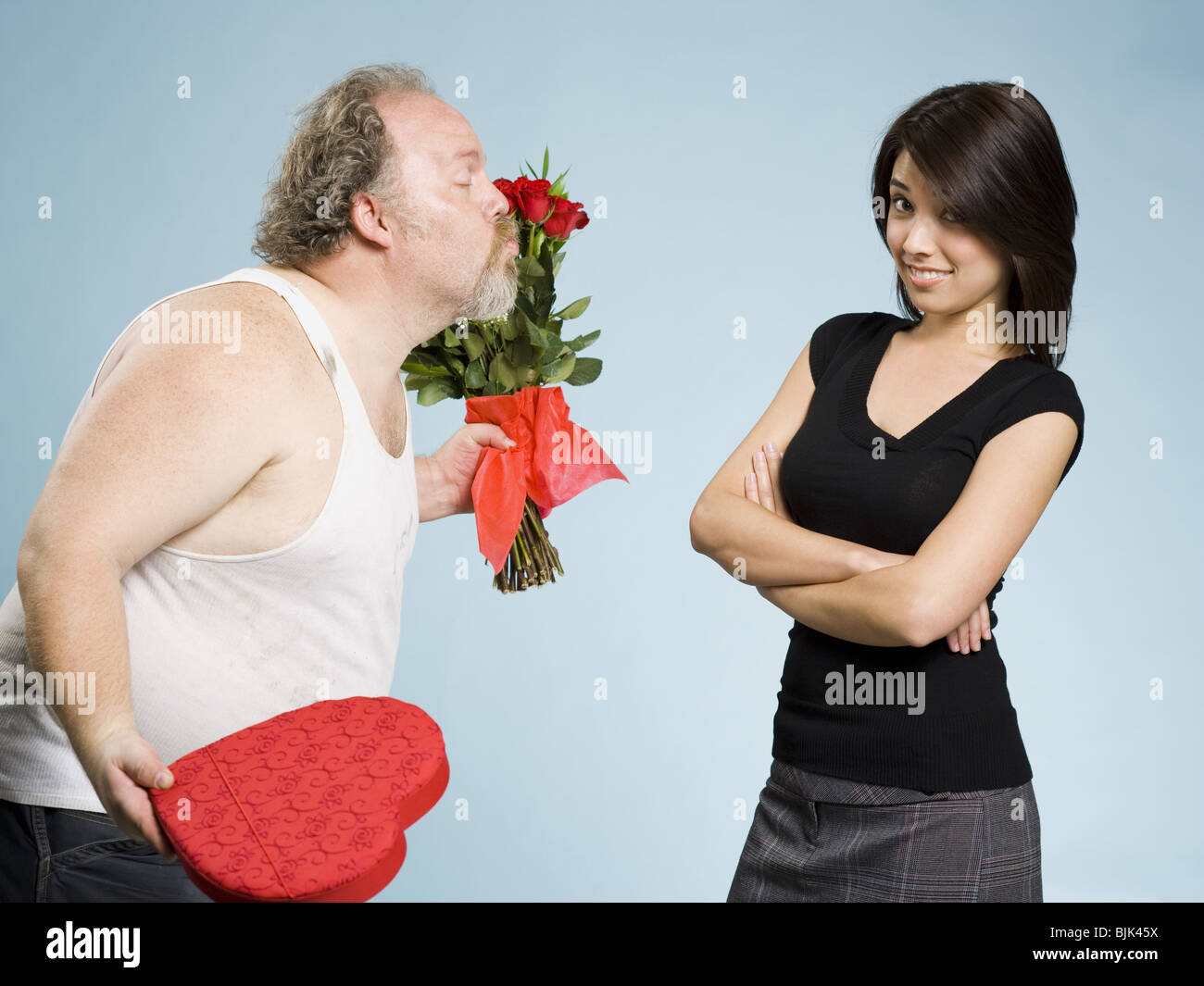 Disheveled man with heart box and red roses with disinterested woman ...
