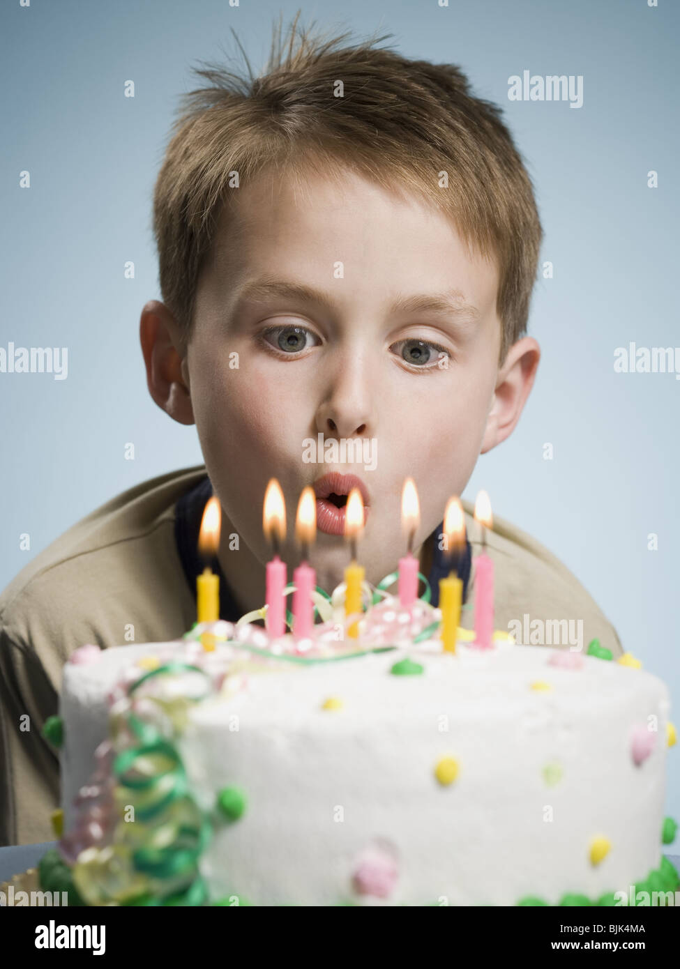 Boy blowing out candles on a birthday cake Stock Photo - Alamy