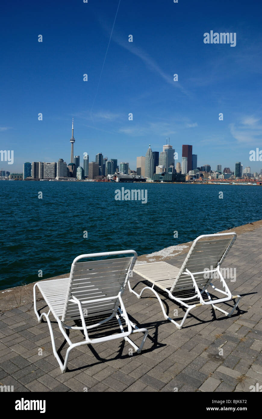 A pair of beach chairs on a promenade overlooking the Toronto skyline ...