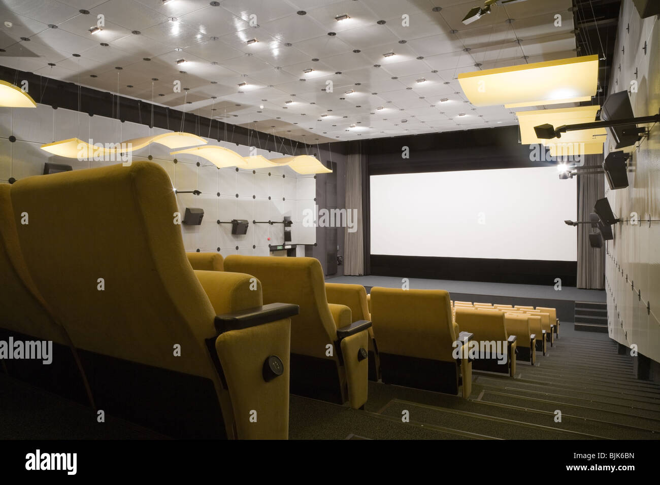 Empty cinema auditorium with line of yellow chairs, stage and ...