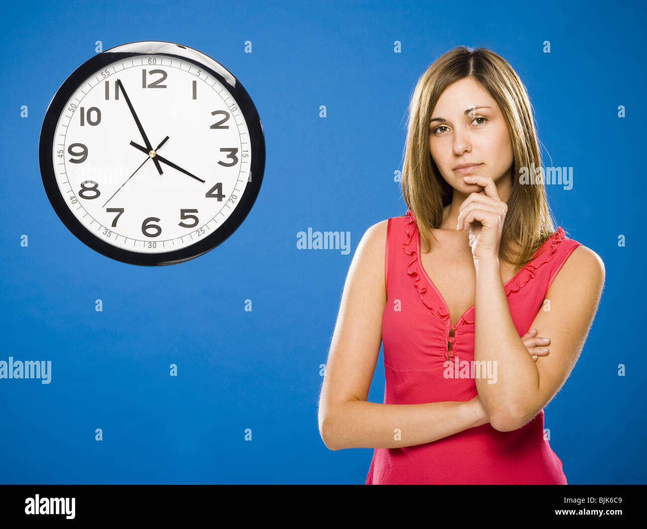 Woman with arms crossed looking at wall clock attached to plumbing ...