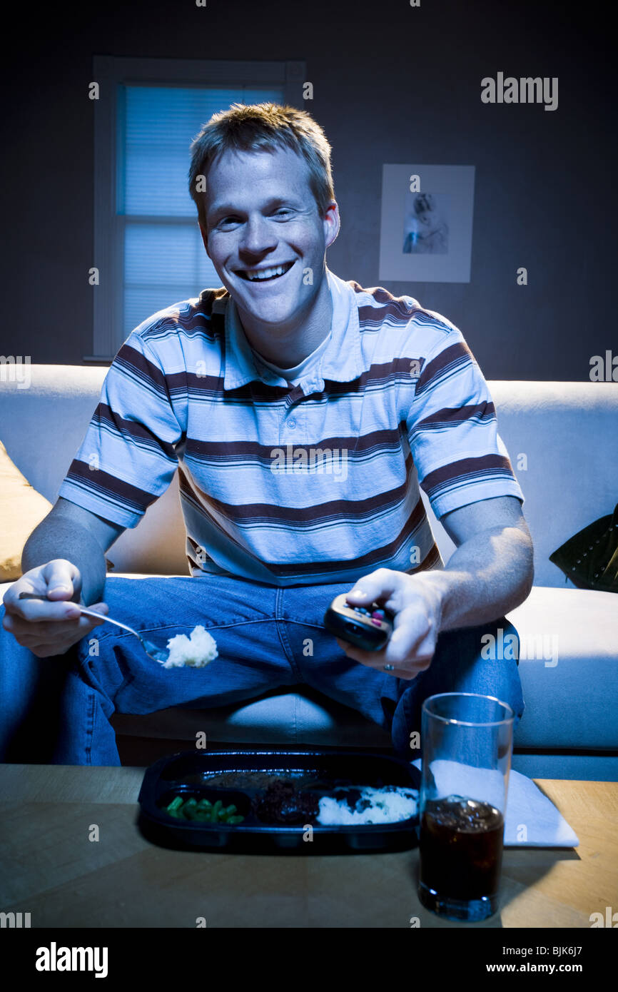 Man on sofa with frozen dinner and napkin with food smiling Stock Photo ...