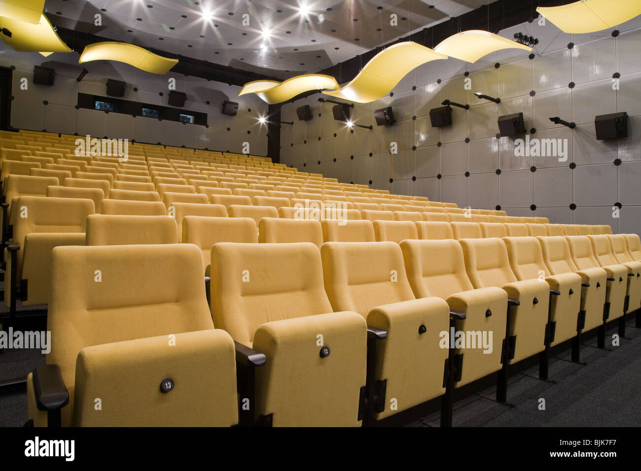 Interior of cinema auditorium with stairs and lines of yellow chairs ...