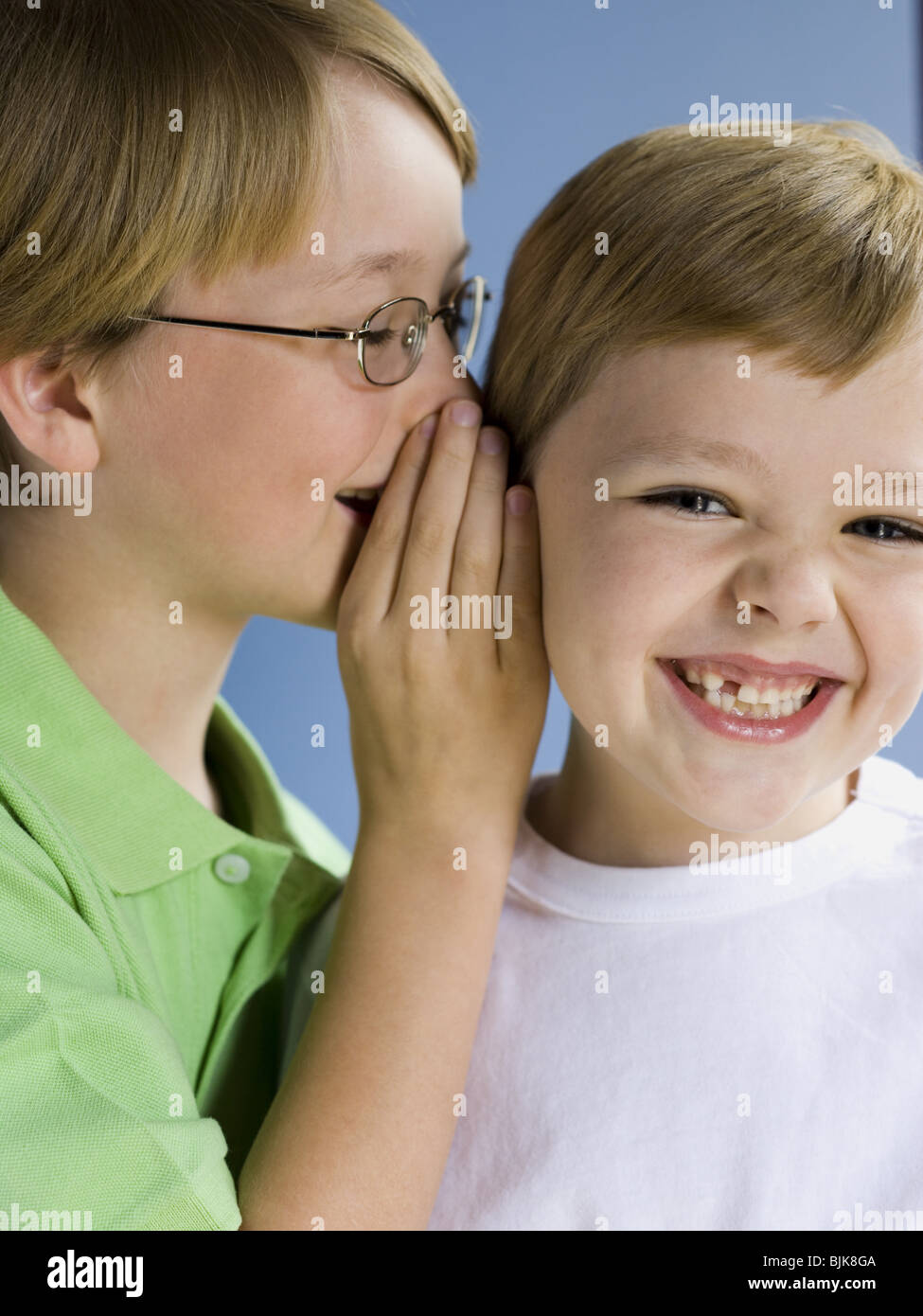 Boy whispering to smiling boy Stock Photo - Alamy