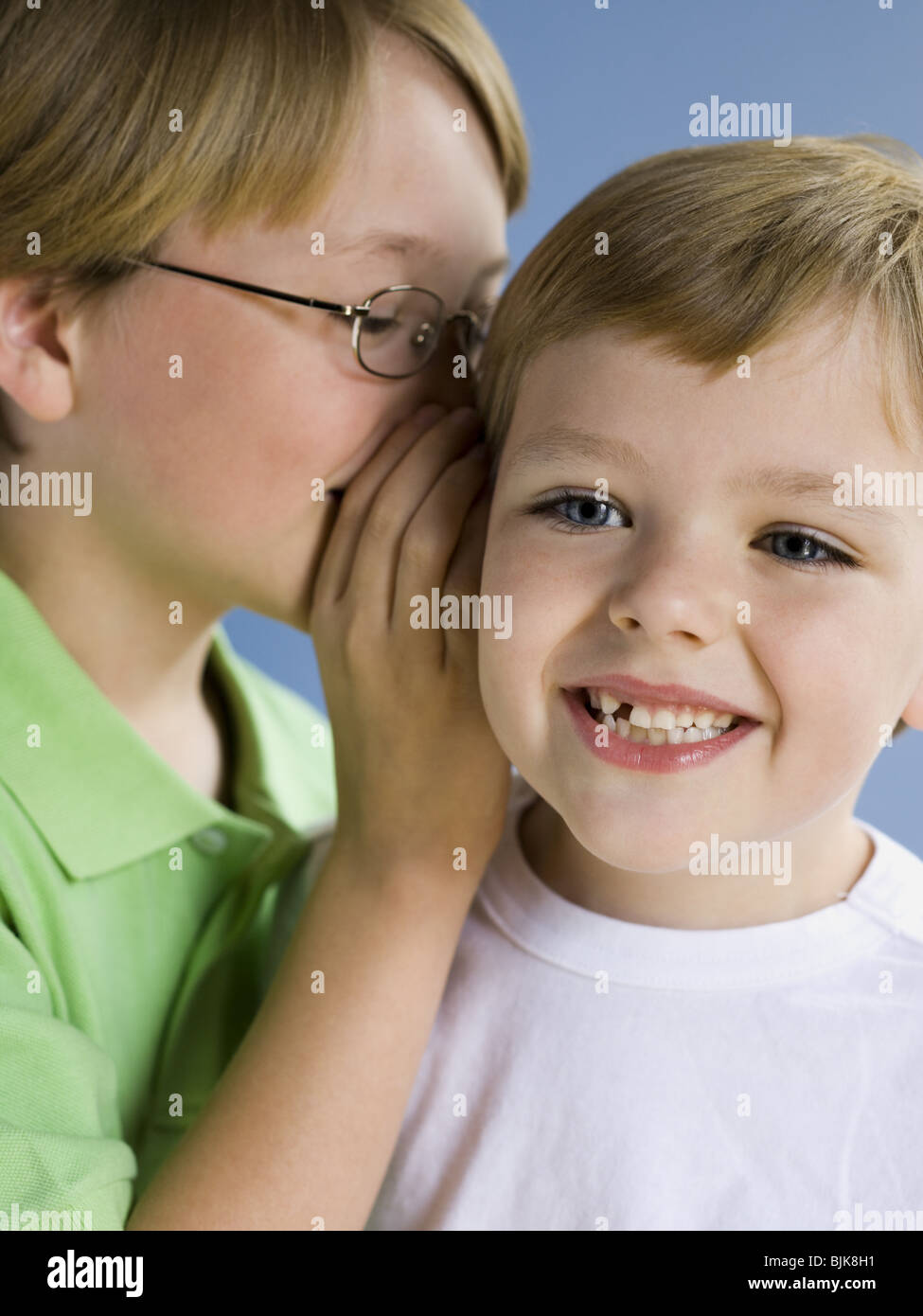 Boy whispering to smiling boy Stock Photo - Alamy