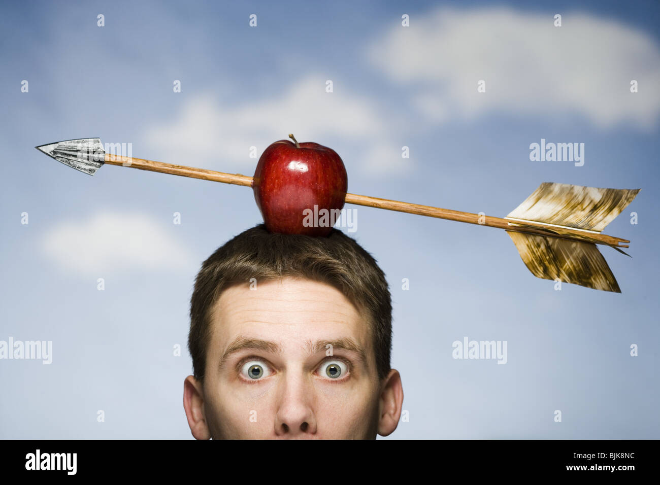 Man outdoors with arrow through red apple on head Stock Photo - Alamy