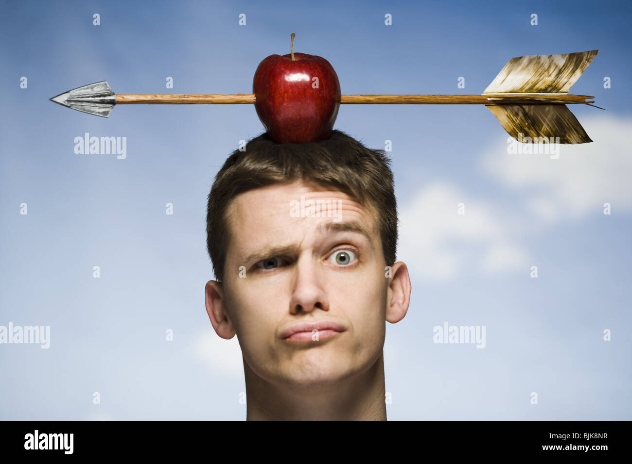 Man outdoors with arrow through red apple on head Stock Photo - Alamy