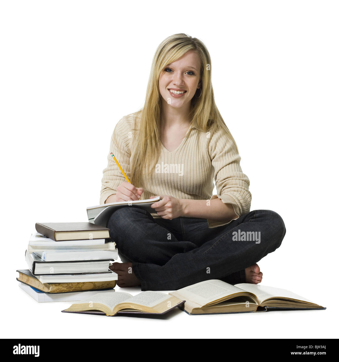 Girl sitting cross legged doing homework smiling Stock Photo - Alamy